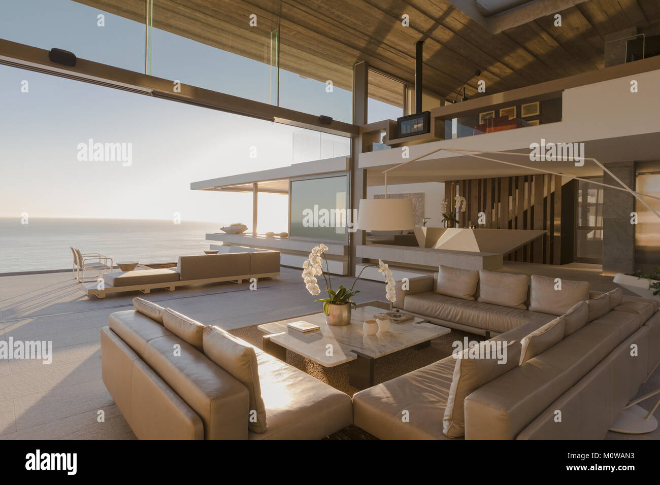 Sunny modern, luxury home showcase interior living room open to ocean ...