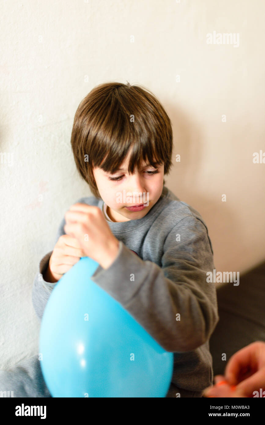 child with inflated blue balloon for party sitting on sofa Stock Photo ...