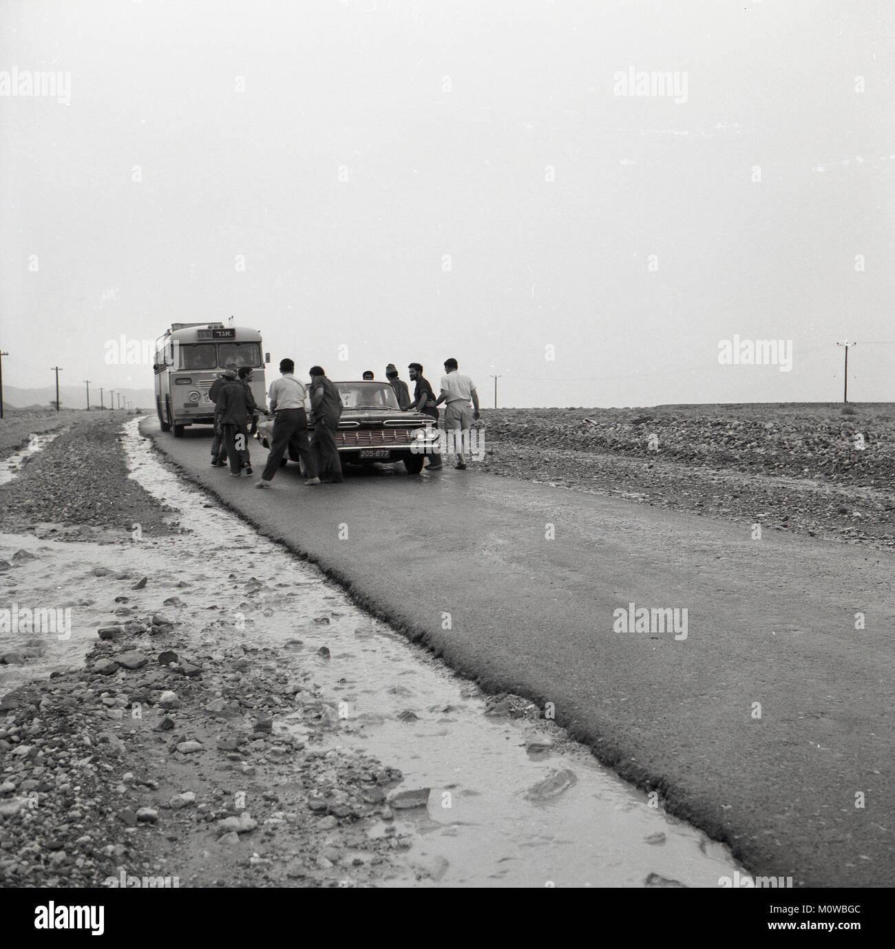 1960s, historical, Israel, coach passengers helping to push a car on a ...