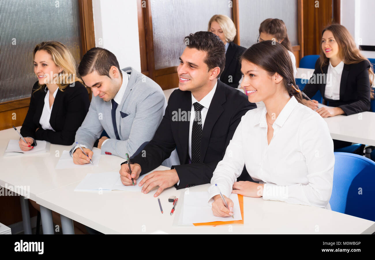 Attentive adult students sitting at the desks at business training ...