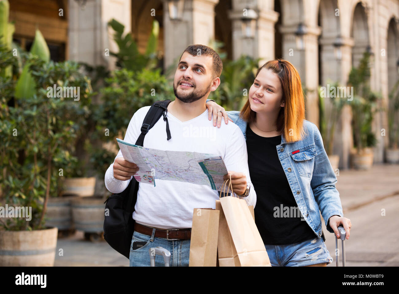 Portrait of happy tourists with package walking with map at street ...