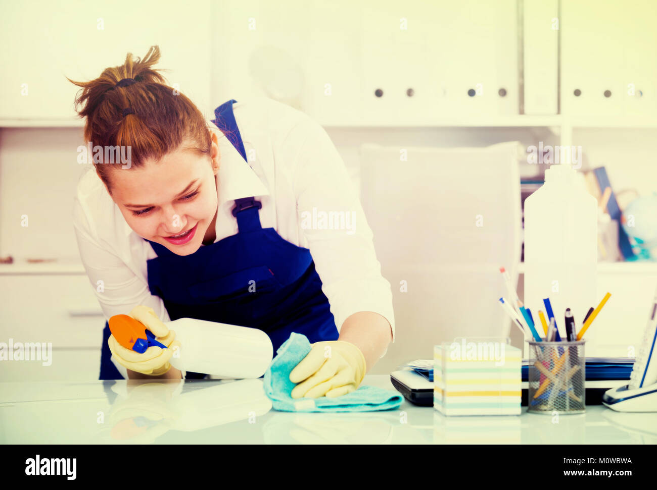 Happy housekeeper is cleaning dust from the desk in the office Stock ...