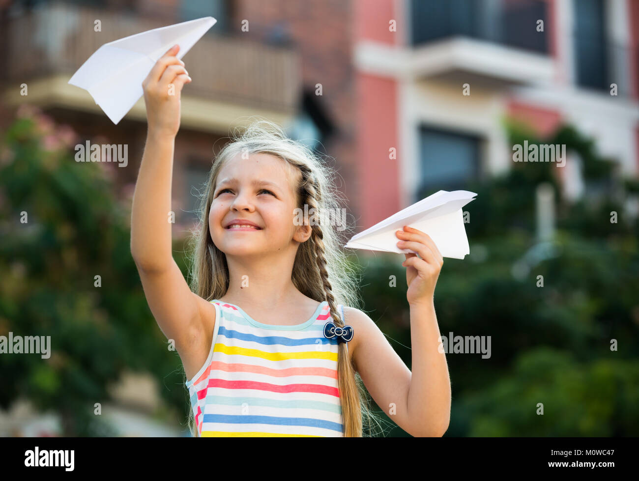 happy girl throwing simple paper airplane toy in air on sunny day Stock ...