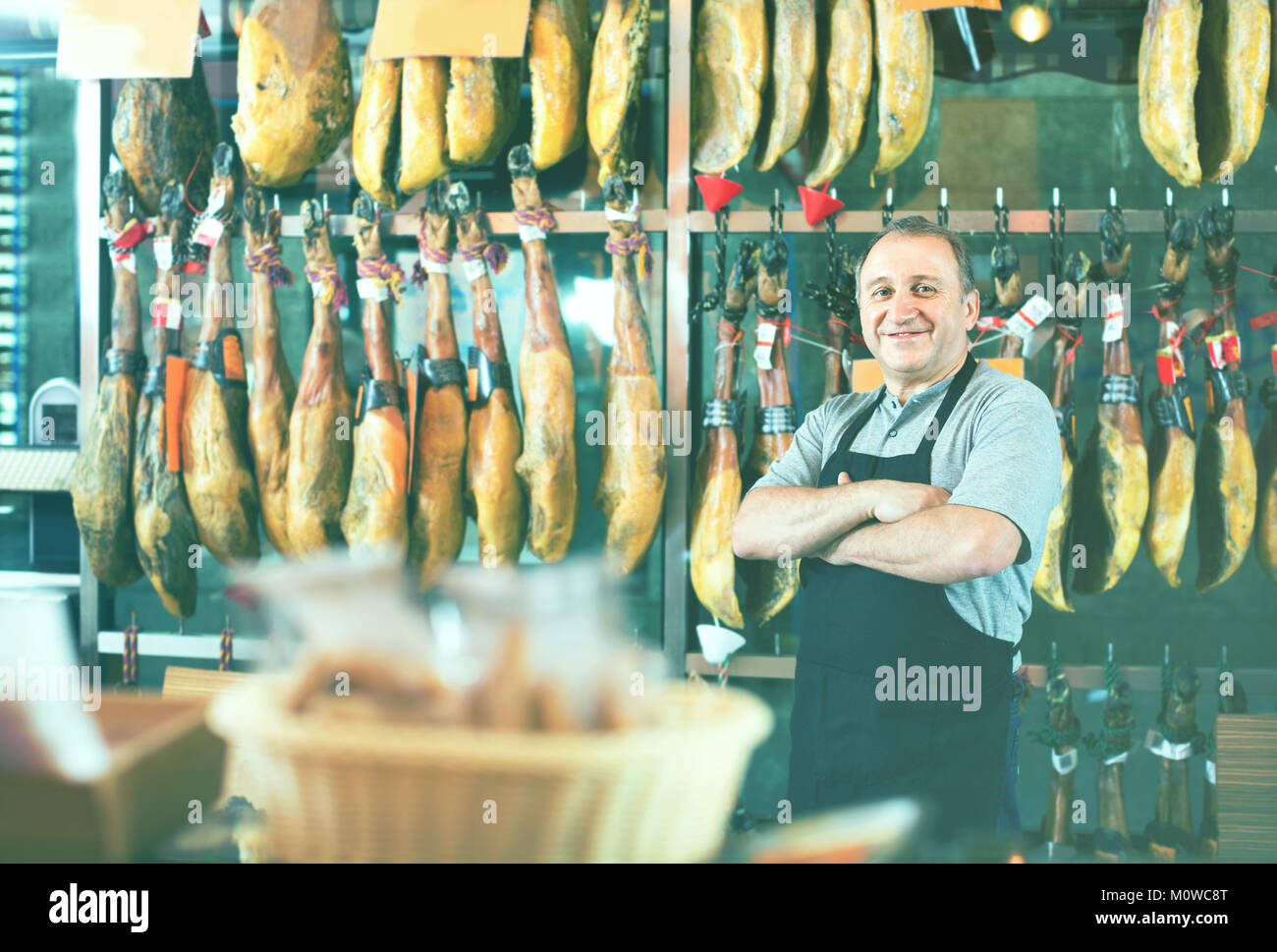 Portrait of cheerful glad friendly mature shop man offering Spanish ...