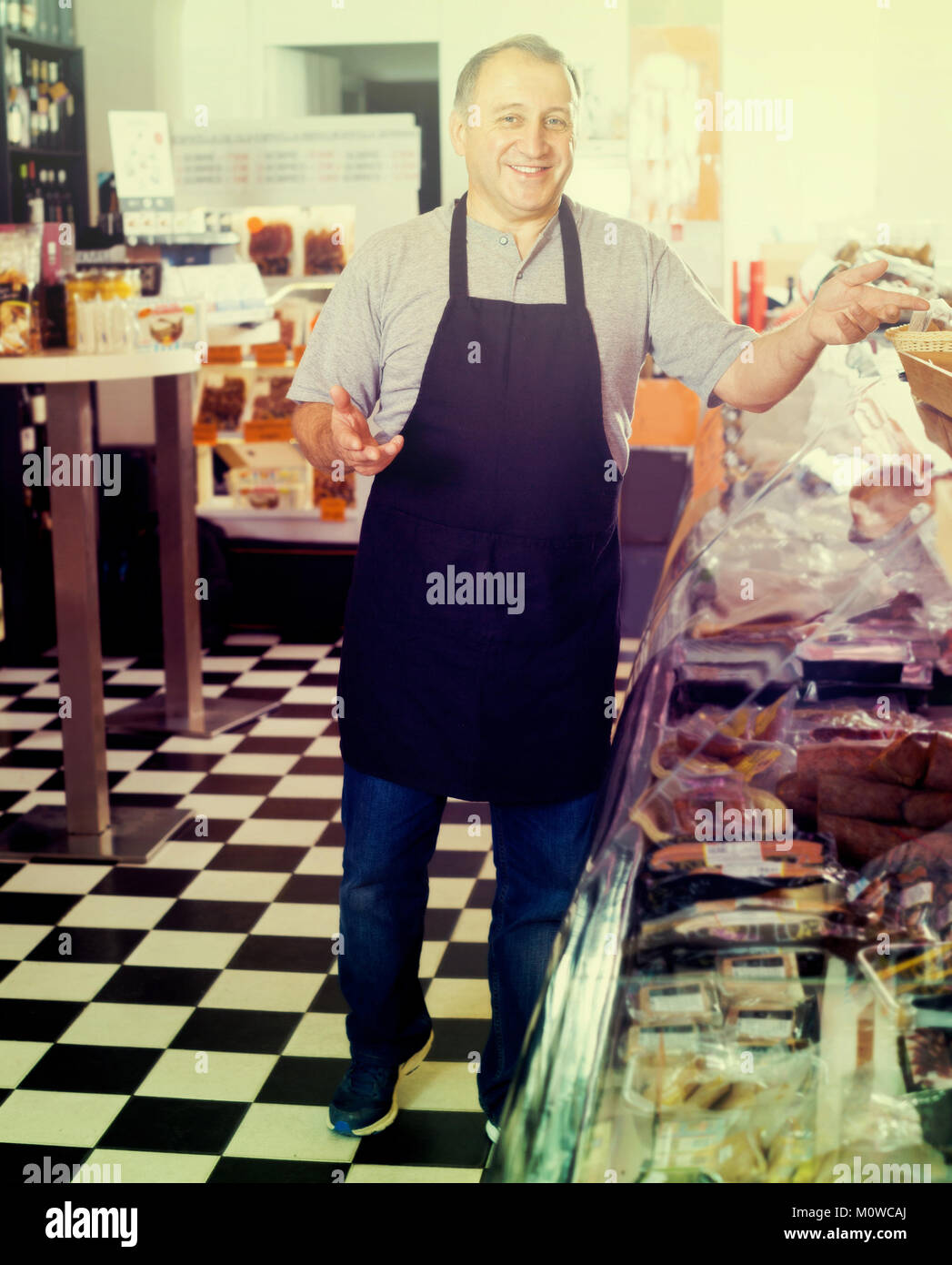 Mature male butcher 55-60 years old with wurst and smoked meat at ...