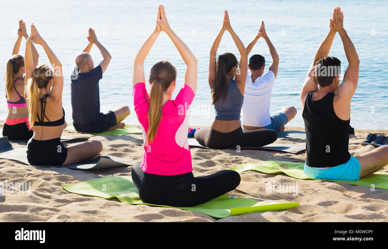 Back view of women and men making yoga meditation in lotus pose on ...