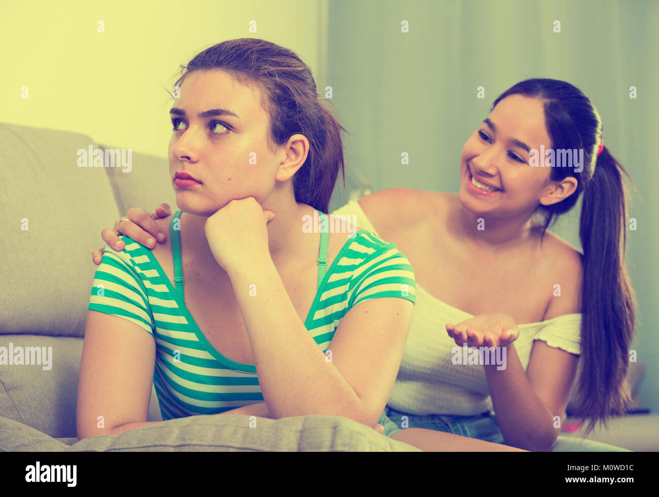 Girl trying to apologize to her offended friend after quarrel on couch ...
