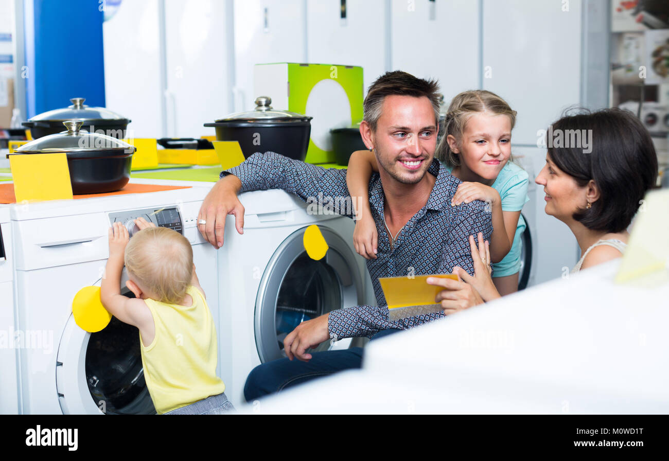 Happy family with two kids together choosing washing machine in shop of ...