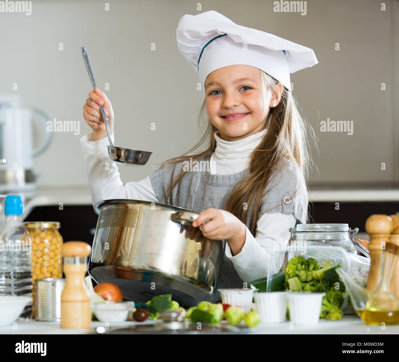 Happy little girl preparing soup for first course at home Stock Photo ...