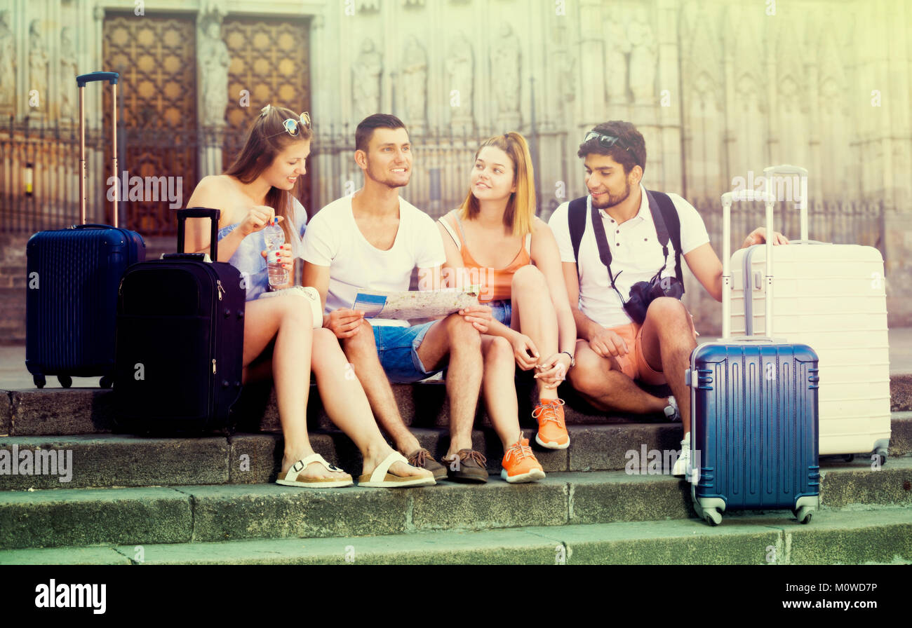 Group of young traveling people searching for direction using paper map ...