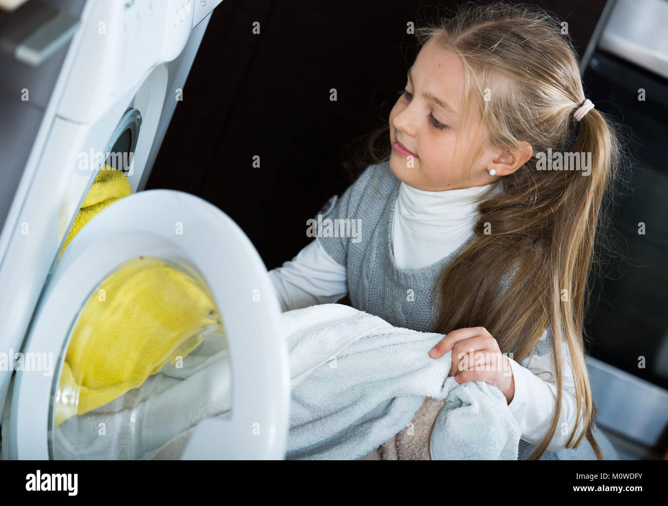 Happy little girl doing laundry in home interior Stock Photo - Alamy
