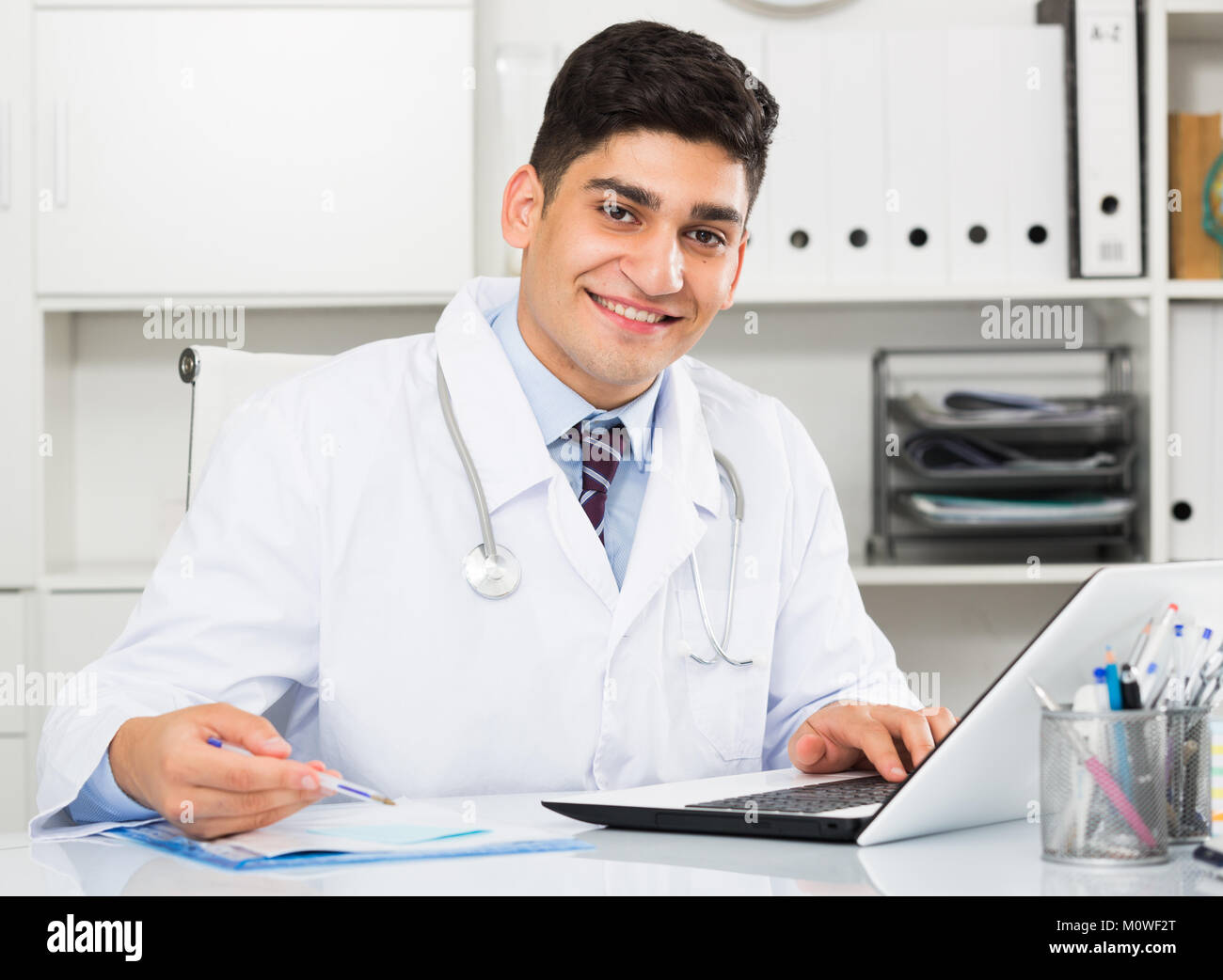 Young smiling doctor is doing report about patients in hospital Stock ...