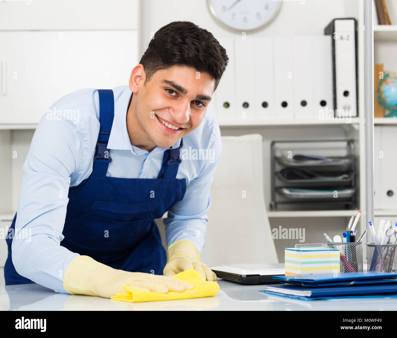 Man cleanaer is cleaning dust from the desk in the office Stock Photo ...
