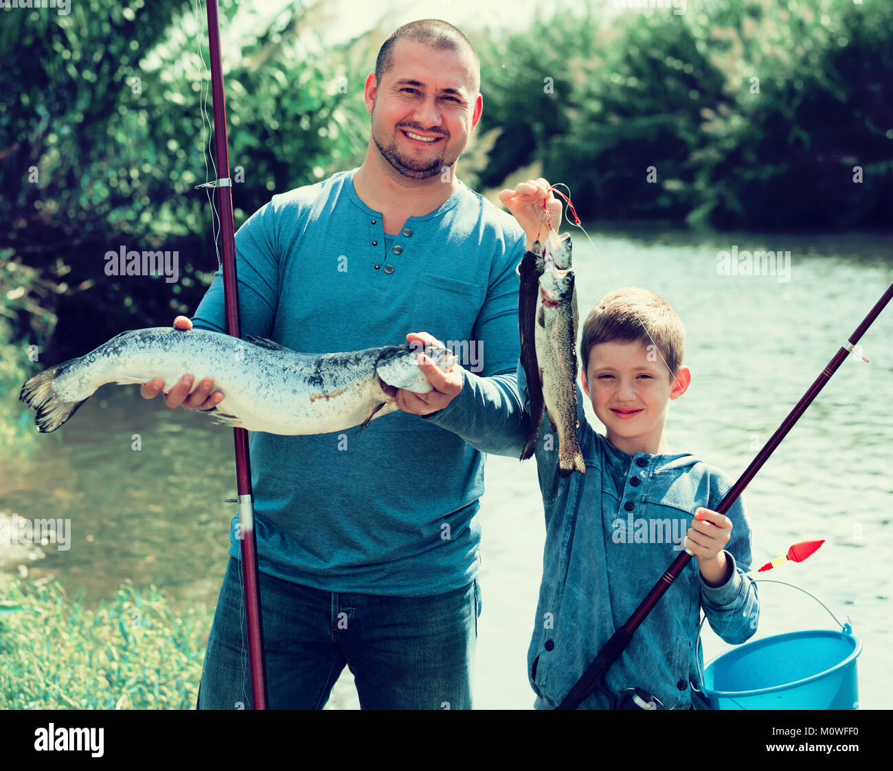happy father and teenager son showing catched fish in wild river Stock ...