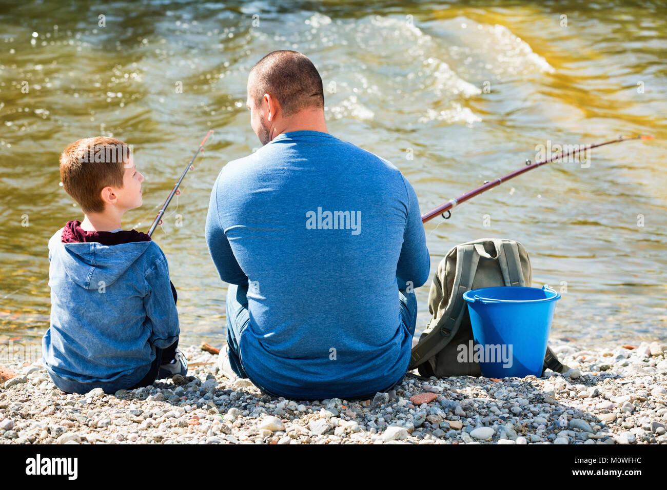 Portrait of satisfied happy friendly father and son fishing with rods ...