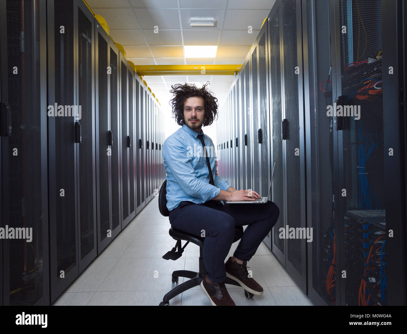 Male IT engineer working on a laptop in server room at modern data ...