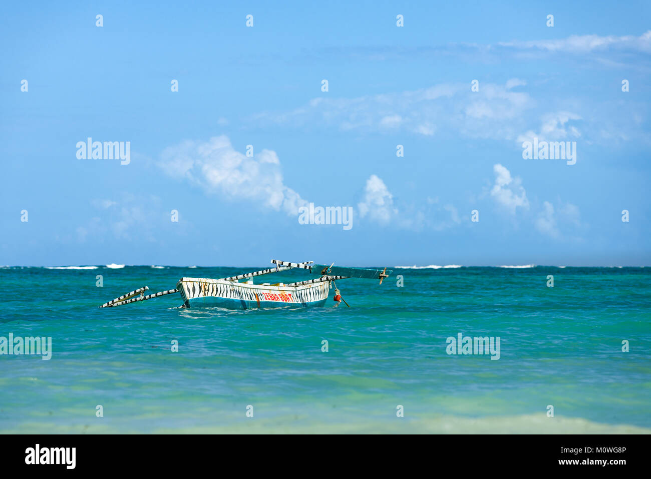 A traditional wooden dhow fishing boat anchored off shore, Diani beach ...