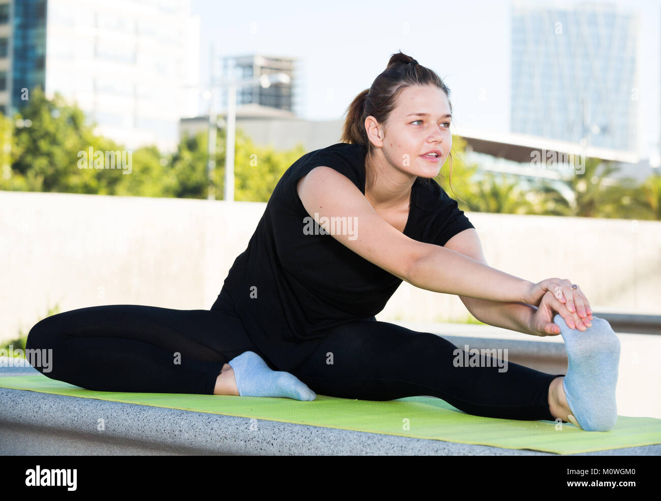 Smiling girl doing workout outdoors on urban landscape background Stock ...
