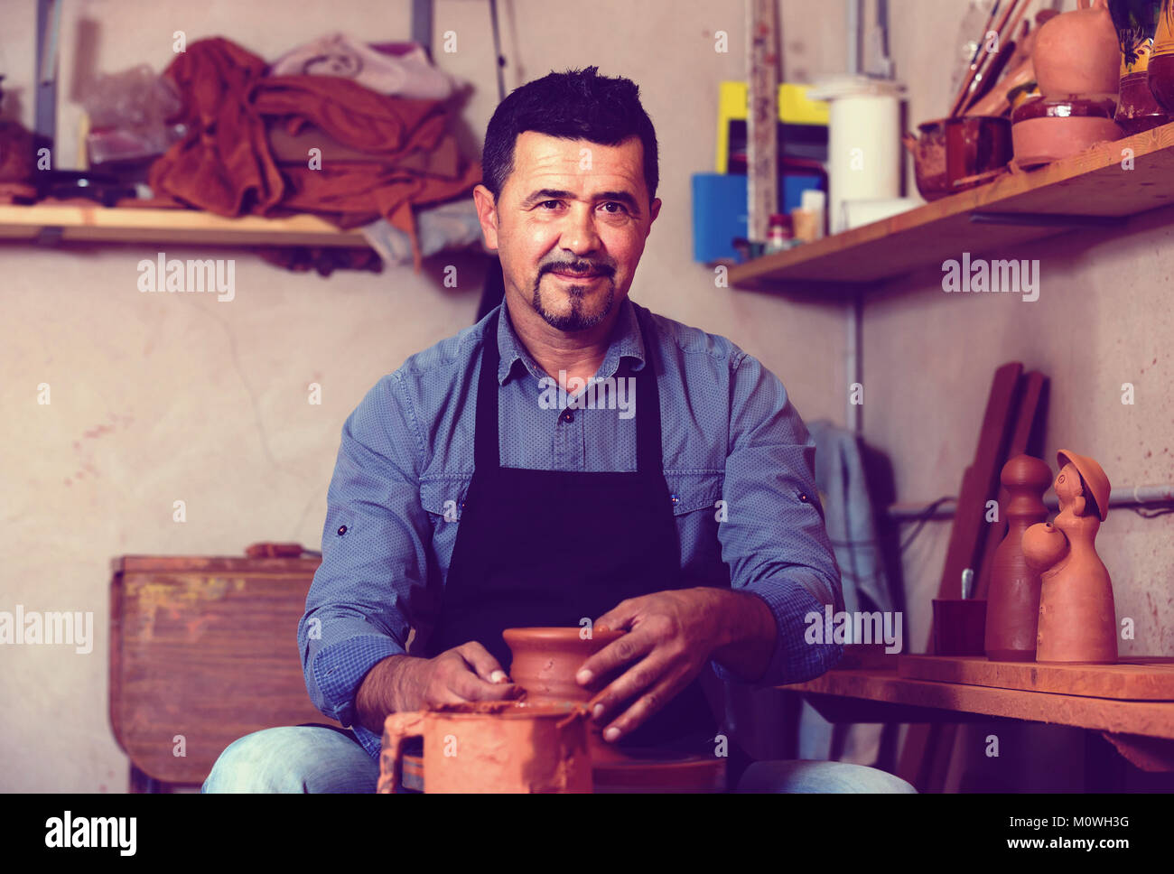 smiling spanish artisan man creating ceramic piece on spinning pottery ...