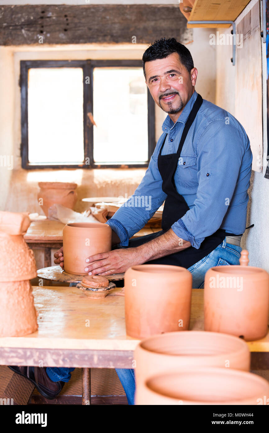 Smiling elderly man making pot using pottery wheel in studio Stock ...