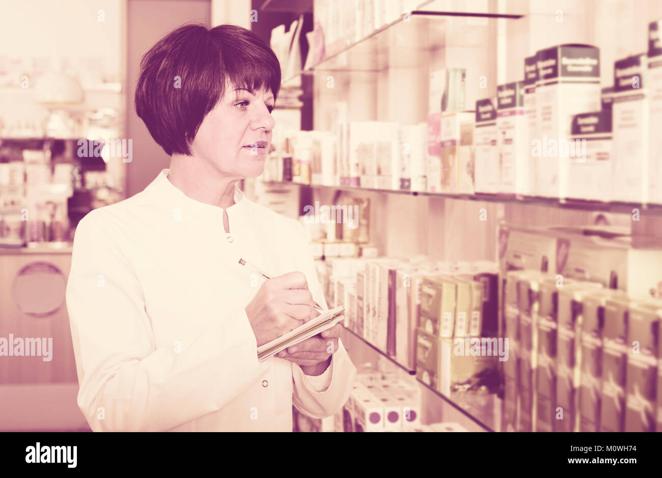 female pharmacist wearing uniform and working in pharmaceutical shop ...