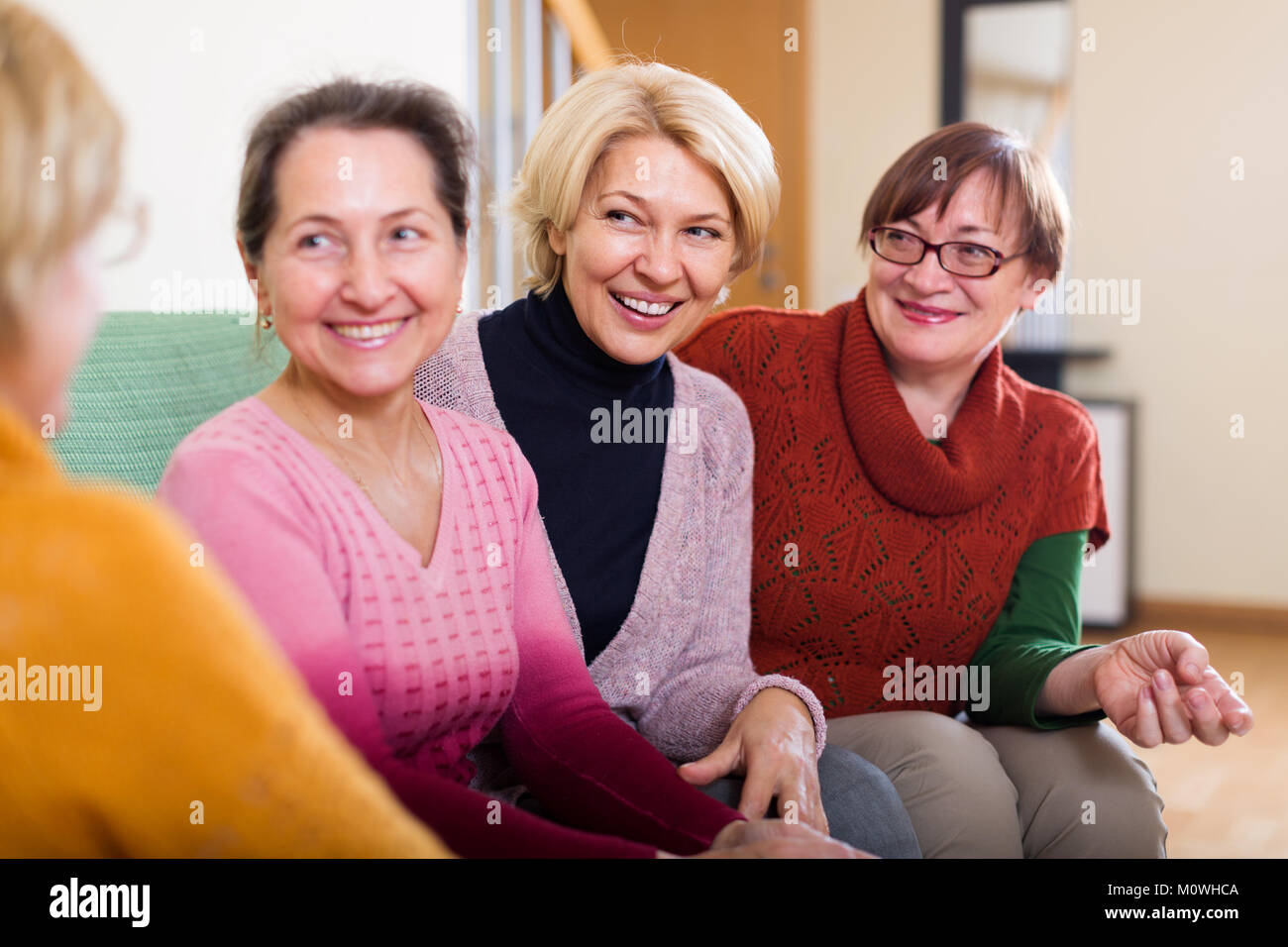 Happy senior friends chatting in room at home Stock Photo - Alamy