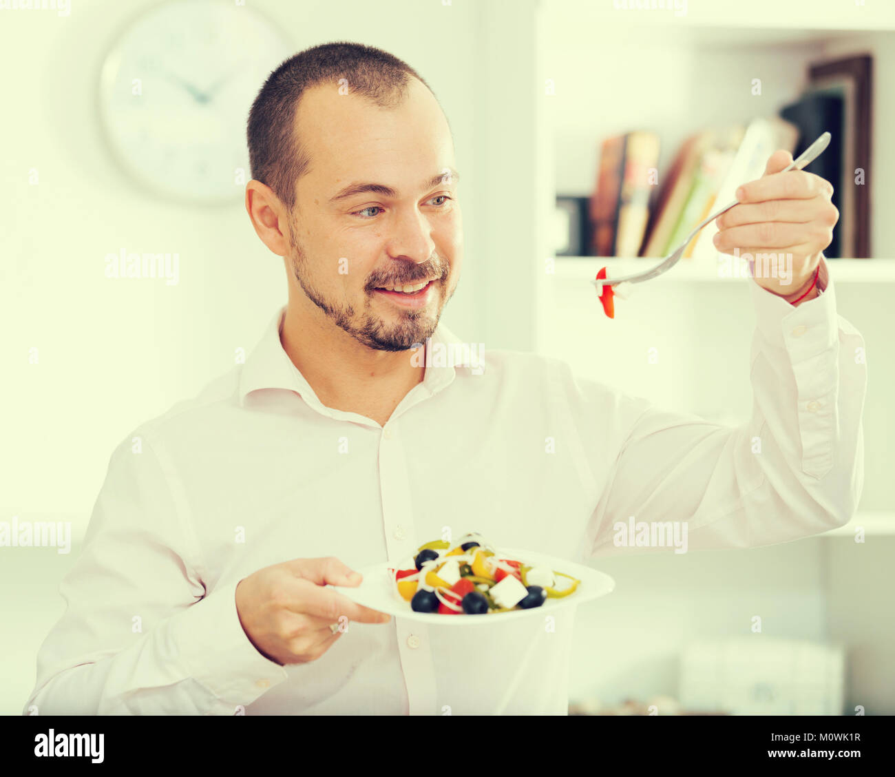 Positive young man ready to eat greek salad in office Stock Photo - Alamy