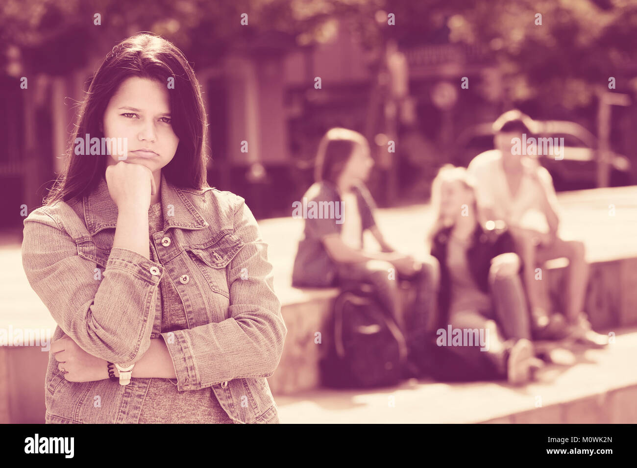 Offended teenage girl standing away from friends feeling depressed ...