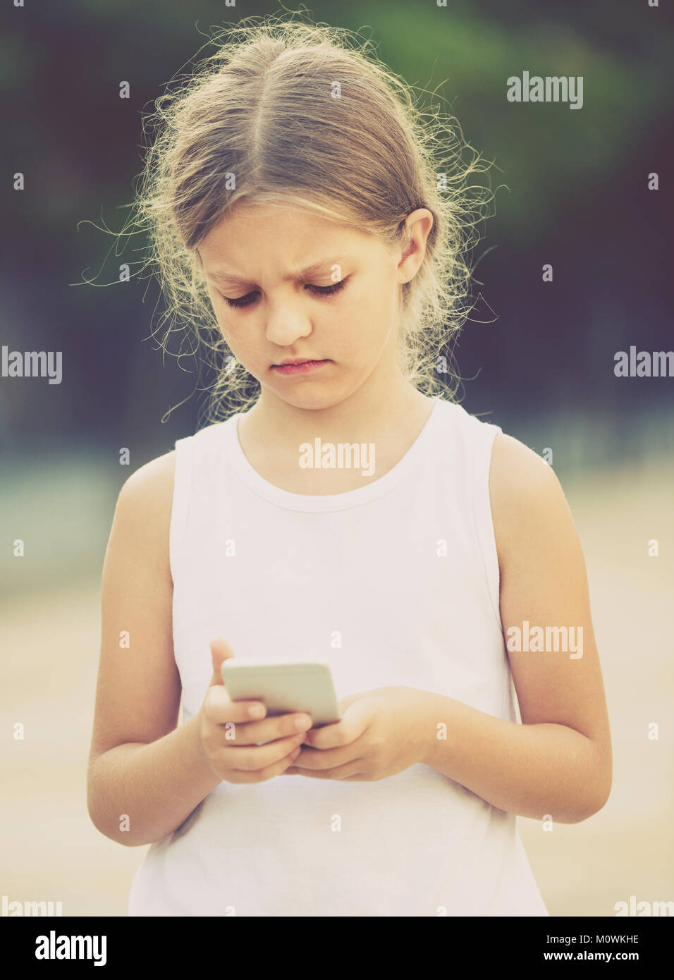 girl looking concerned while looking at mobile phone outdoors on ...