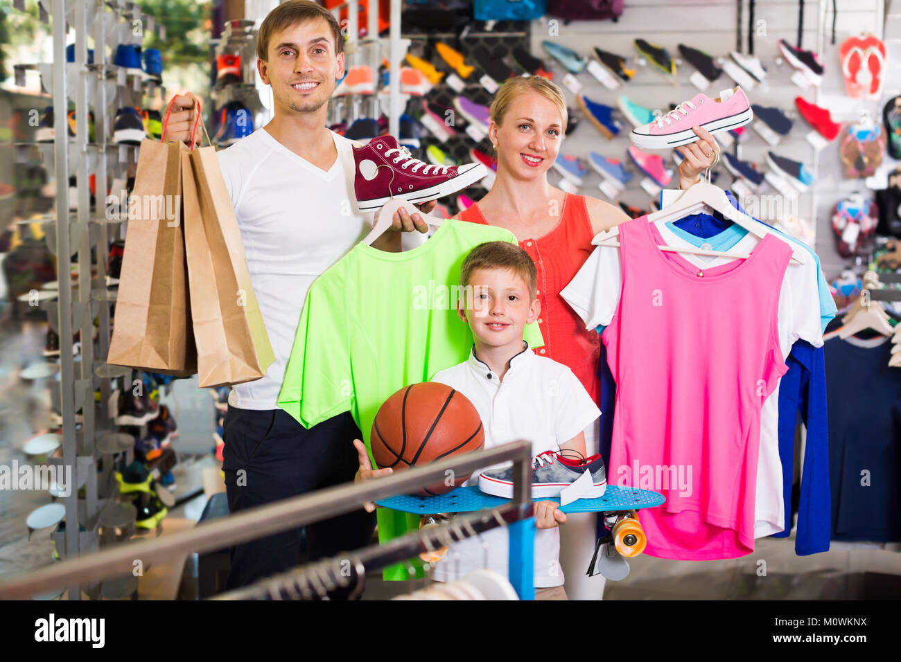 Cheerful adult parents with boy in school age shopping clothing in ...