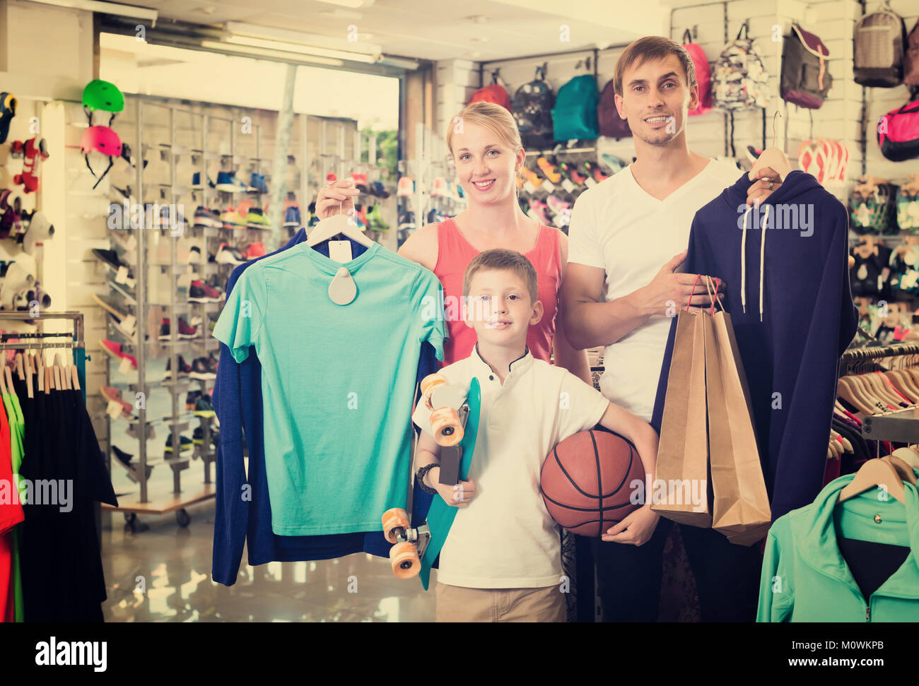 Cheerful young parents with boy in school age shopping clothing in ...