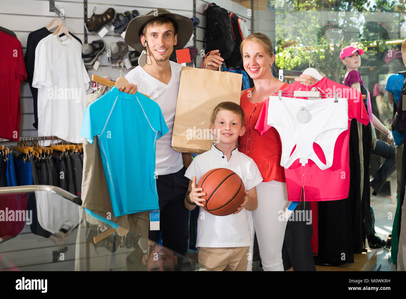 Young positive parents with boy in school age shopping clothing in ...