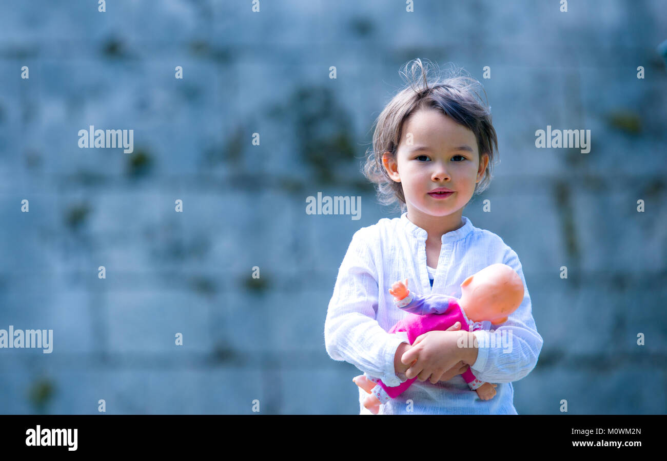 Little girl holding her doll, outdoor Stock Photo - Alamy