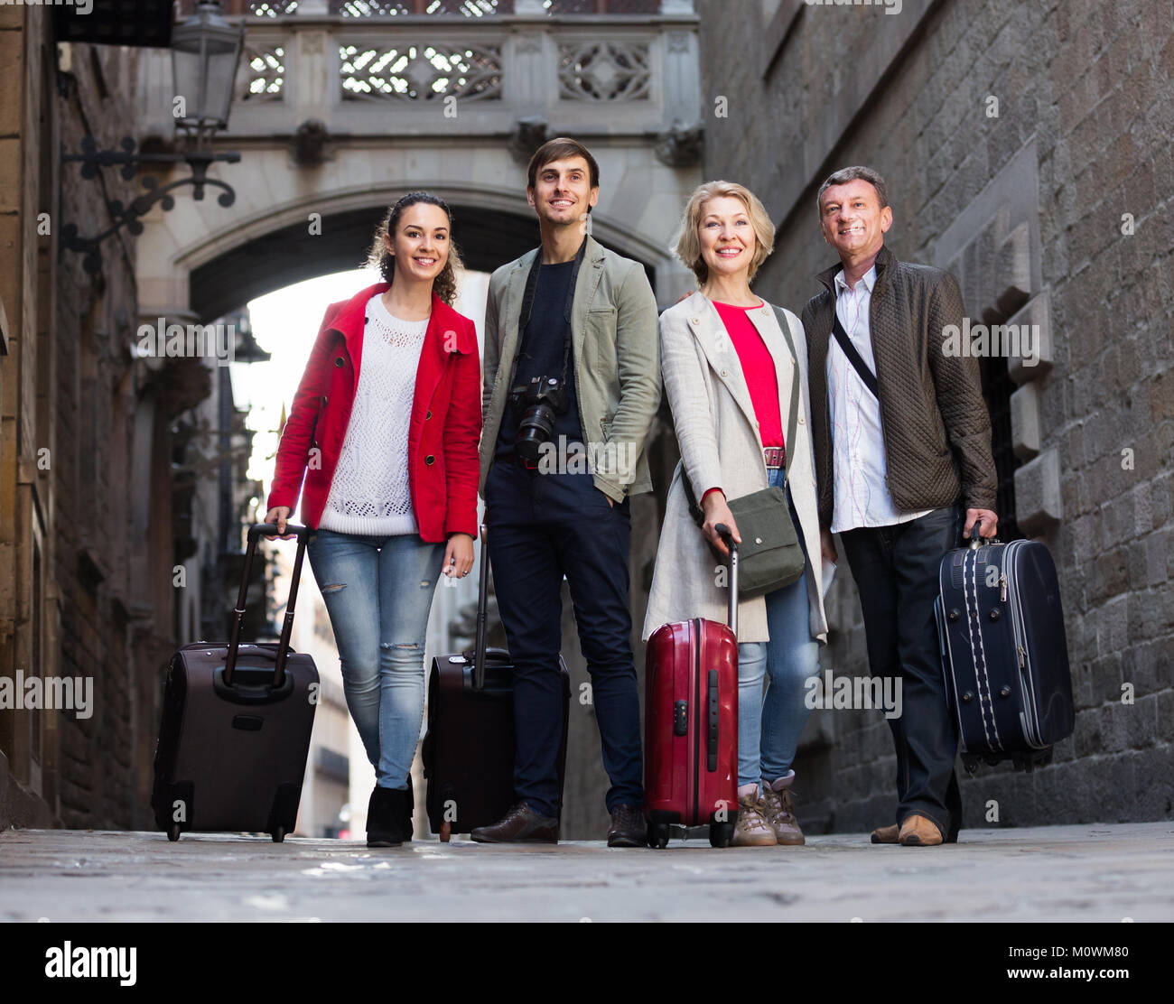 Laughing tourists in casual with luggage pose on the street outdoors ...