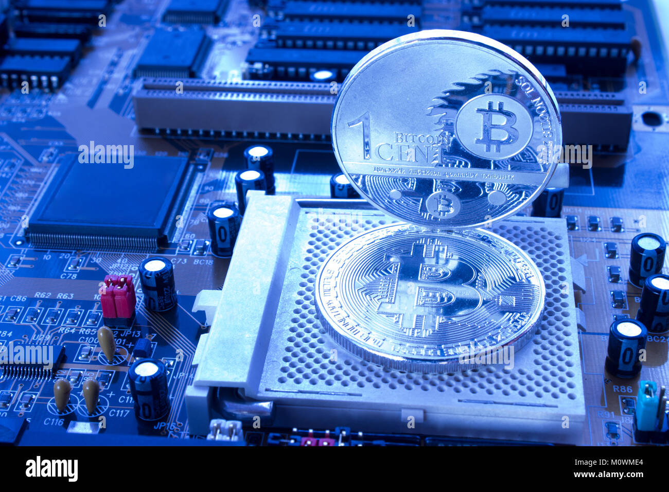 On a printed circuit motherboard are silver coins of a digital crypto ...
