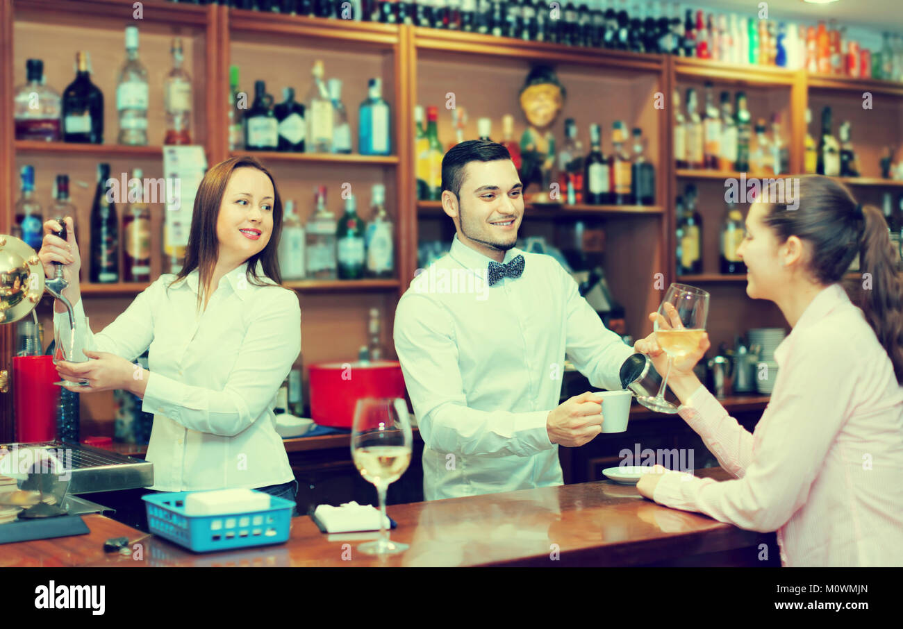 Smiling young girl standing at bar and holding glass of wine. Focus on ...