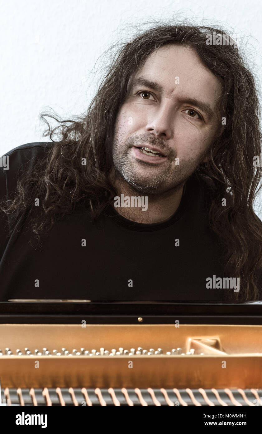 Male musician by the great piano with open top Stock Photo - Alamy