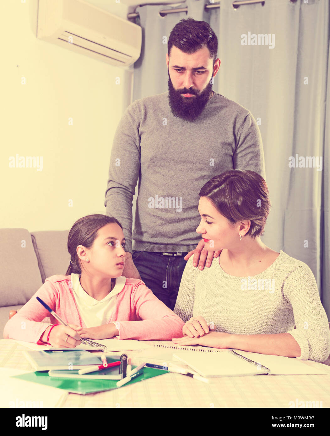 Father and mother helping their child to do homework at home Stock ...