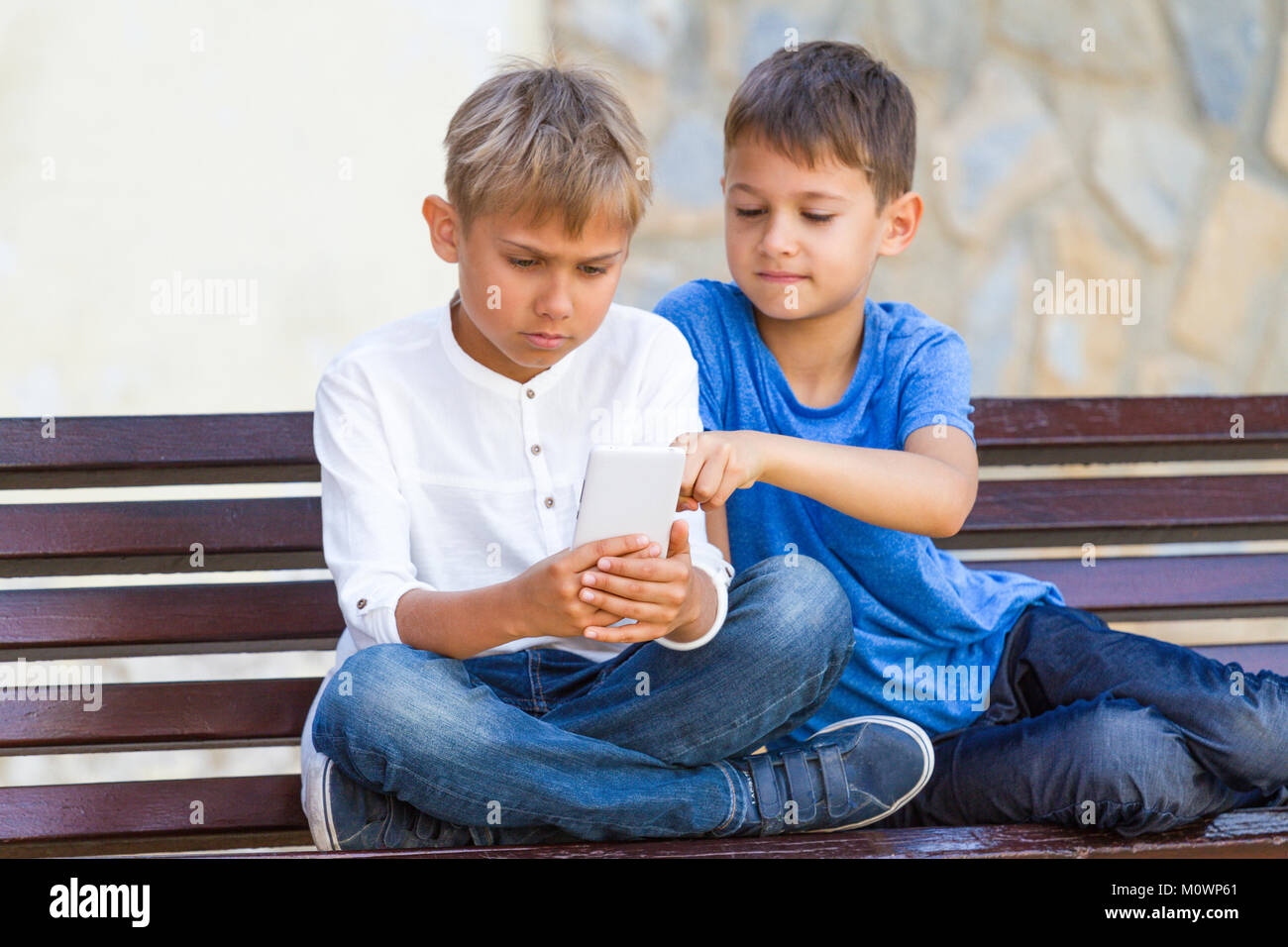 Boys with mobile phone sitting on the bench outdoors Stock Photo - Alamy
