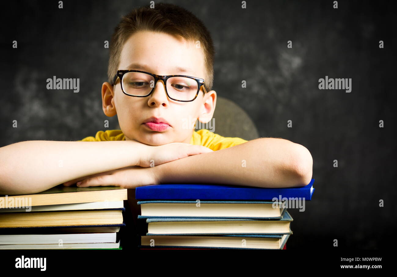 Worried kid taking rest on pile of books Stock Photo - Alamy