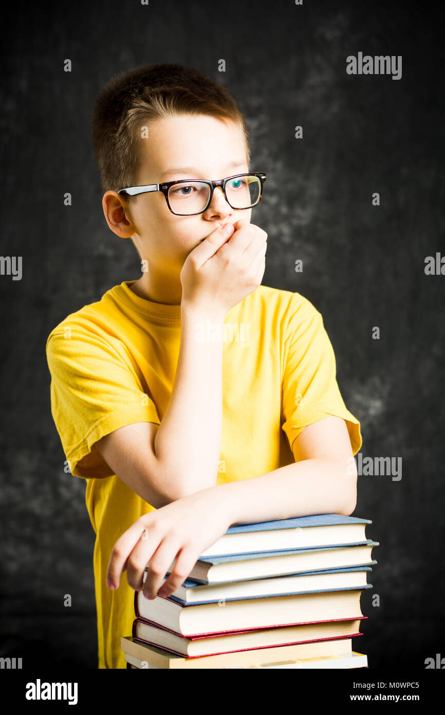 Worried kid taking rest on pile of books Stock Photo - Alamy