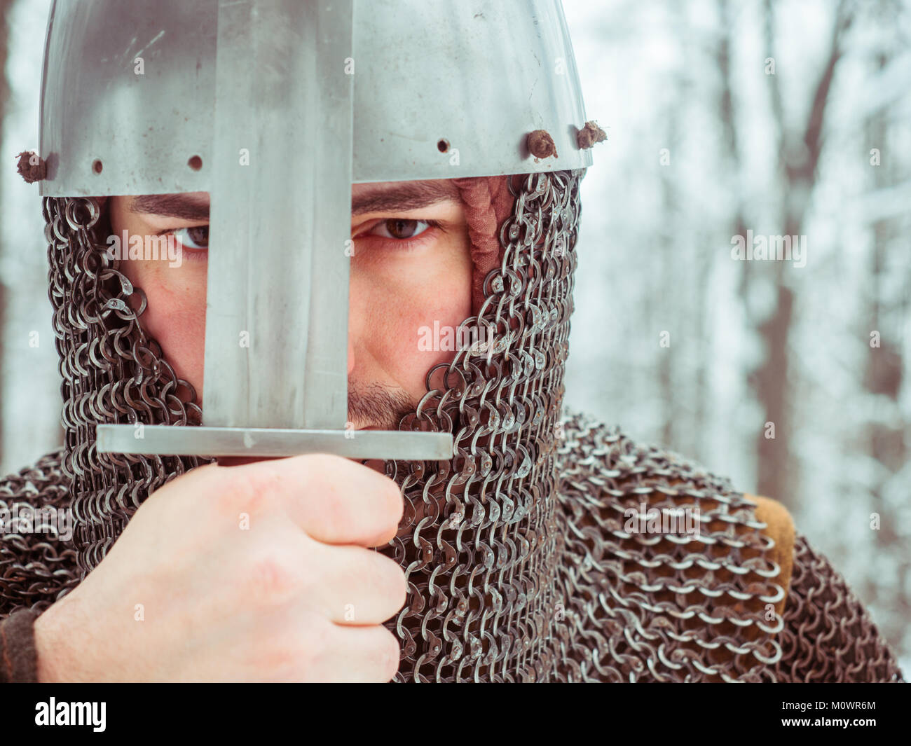Medieval viking warrior in chain mail and helmet holds a sword in the ...