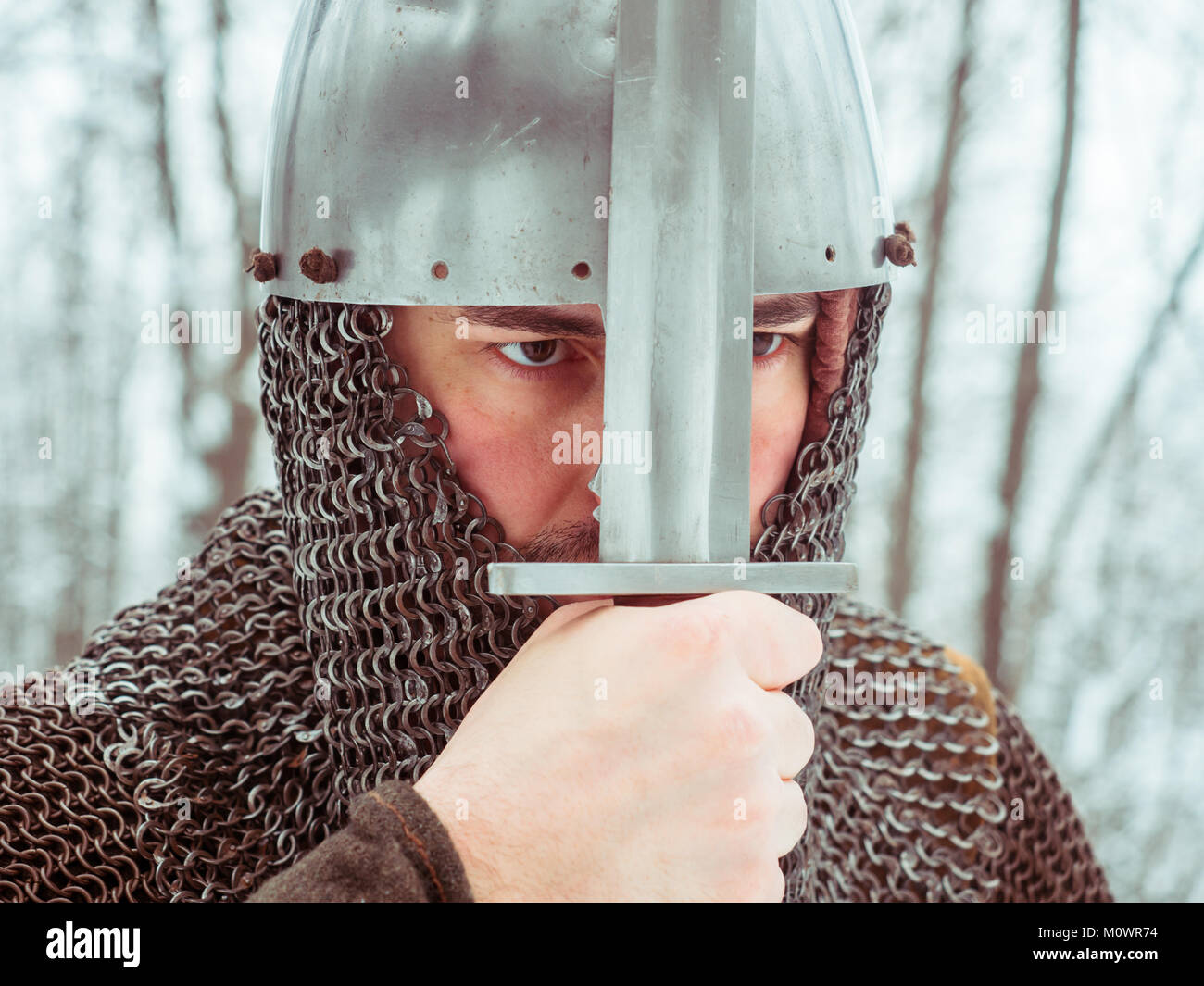 Medieval viking warrior in chain mail and helmet holds a sword in the ...