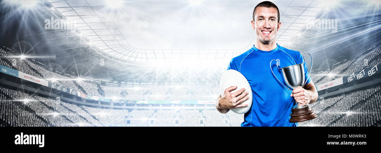 Composite image of portrait of smiling rugby player holding trophy and ...