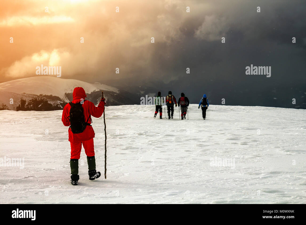 Tourists hikers in winter snow covered mountains and dramatic clouds in ...