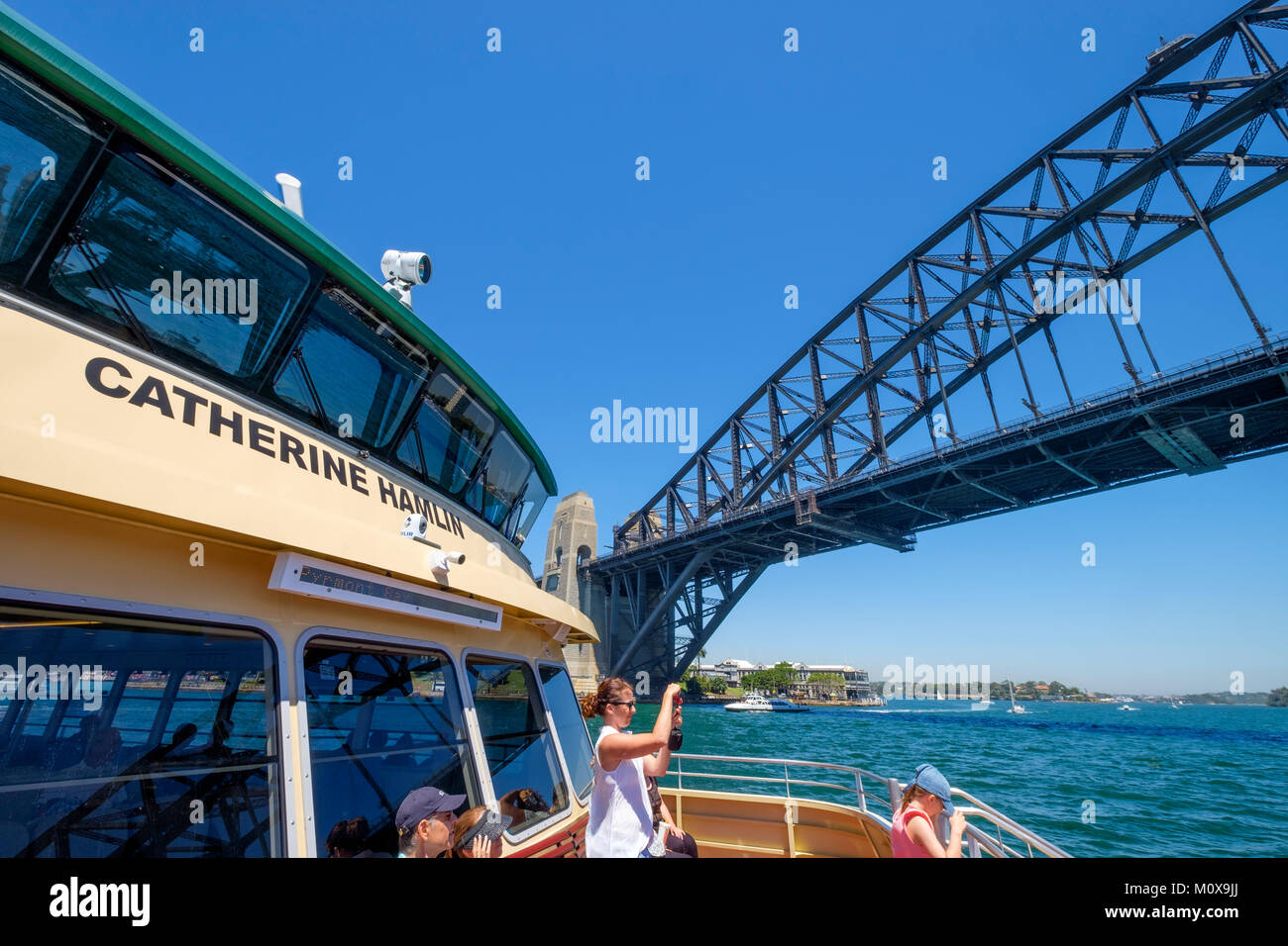 People enjoying ferry ride on a sunny day under Sydney Harbour Bridge ...
