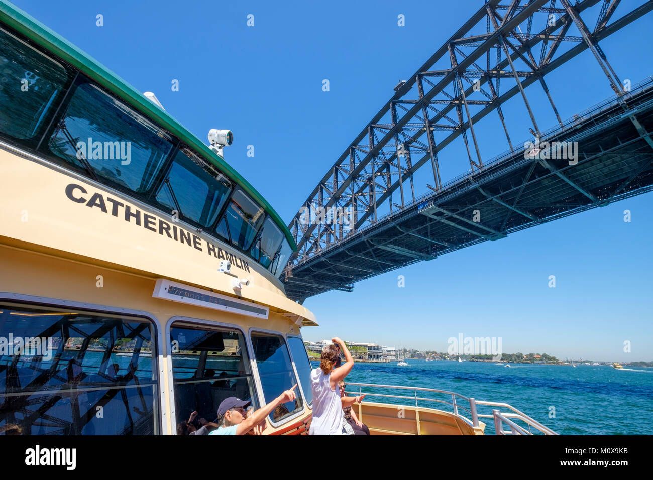 People enjoying ferry ride on a sunny day under Sydney Harbour Bridge ...