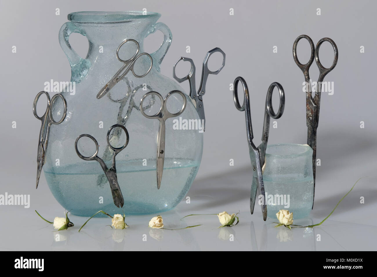 Glass translucent jar of bluish hue and a small glass on a white ...