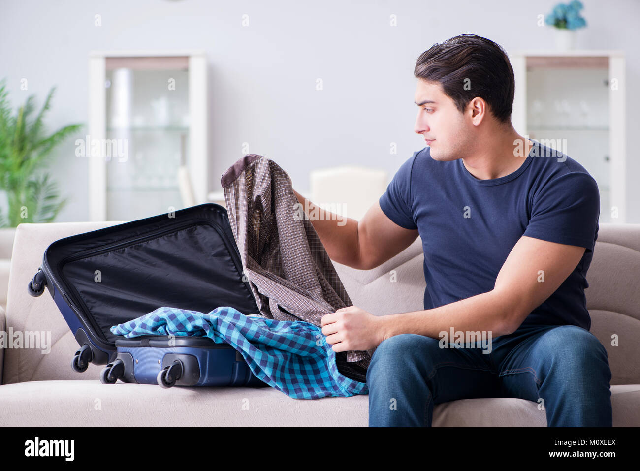Young man preparing packing for summer vacation Stock Photo - Alamy