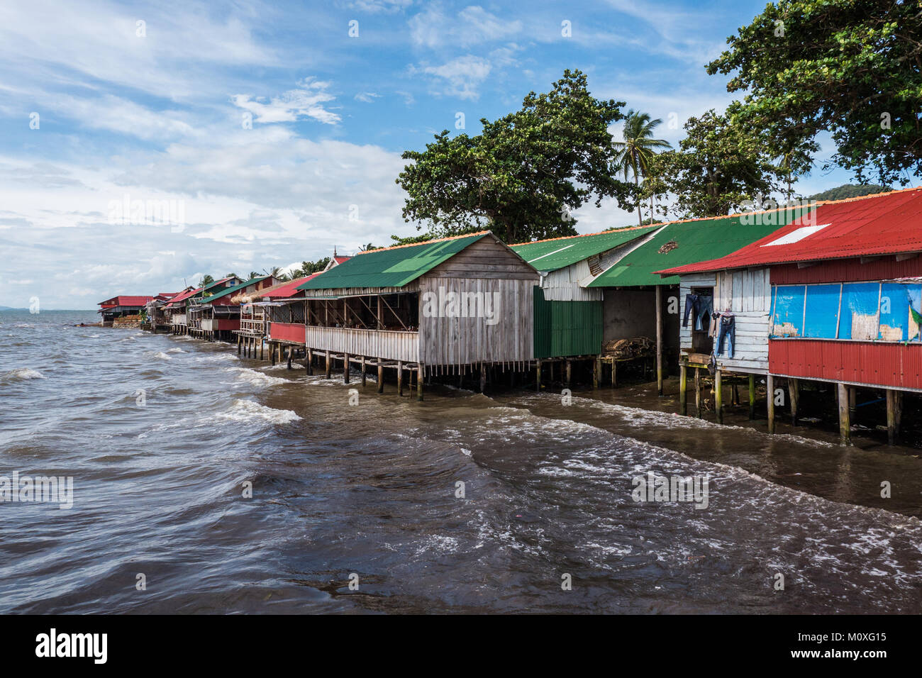 A line of crab and seafood restaurants lined along the muddy beach in ...